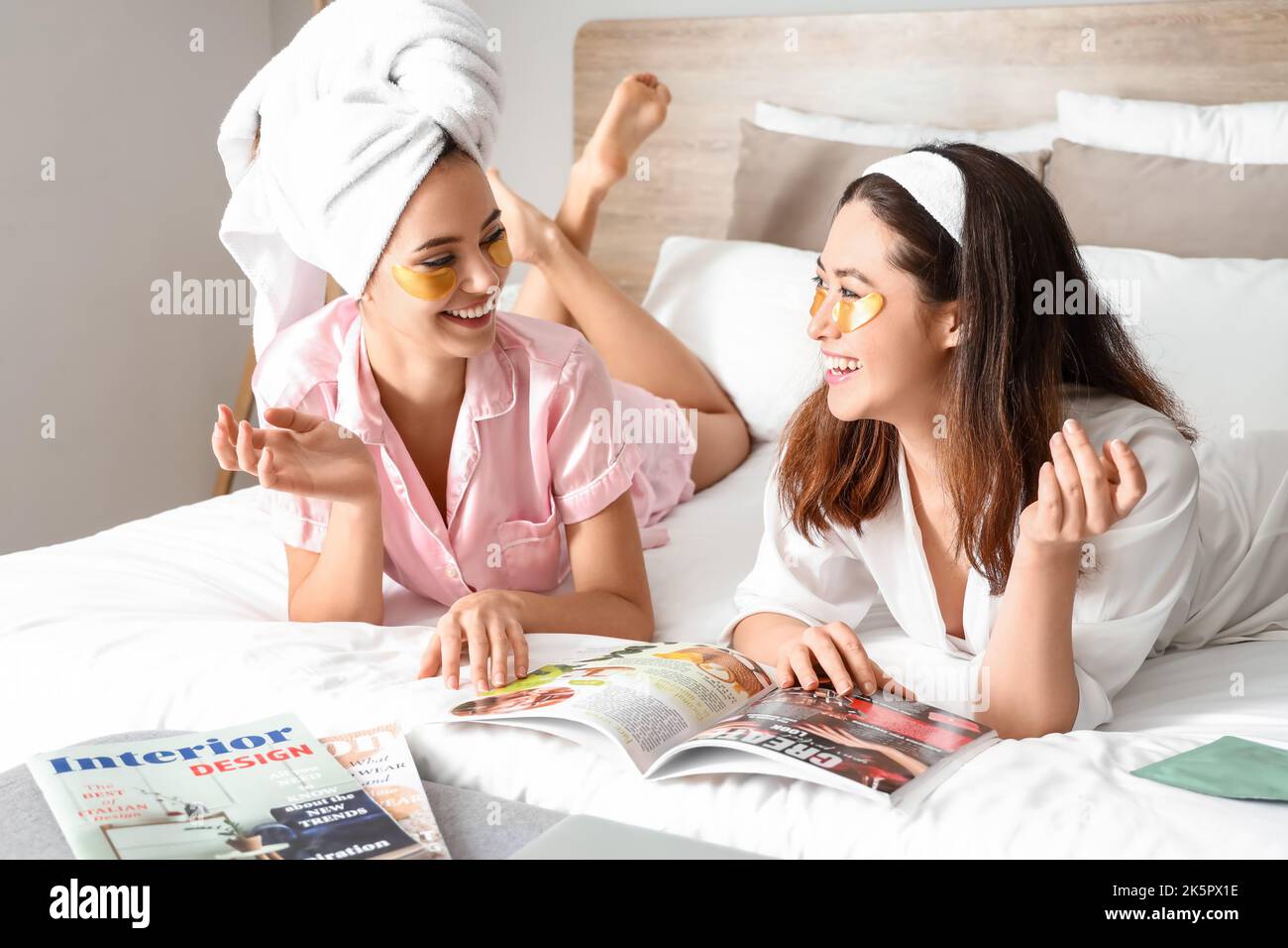 Beautiful young women with under-eye patches reading magazine in ...