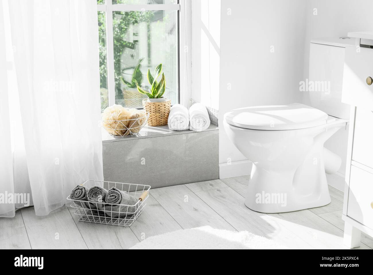 Modern toilet bowl and towels near window in bathroom interior Stock ...