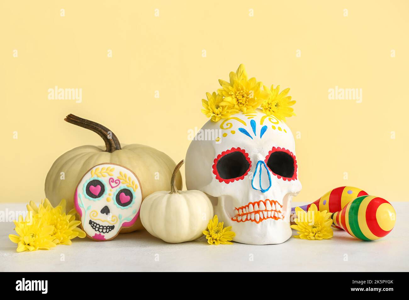 Painted human skull with flowers, pumpkins and maracas on table near ...