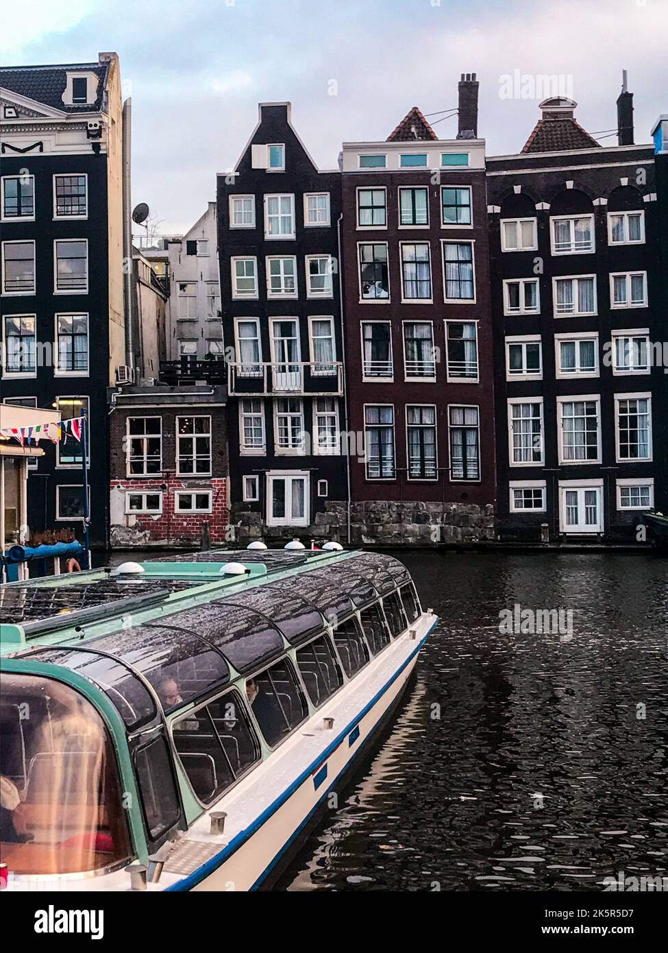 A vertical shot of the canals of Amsterdam with crooked canal buildings ...