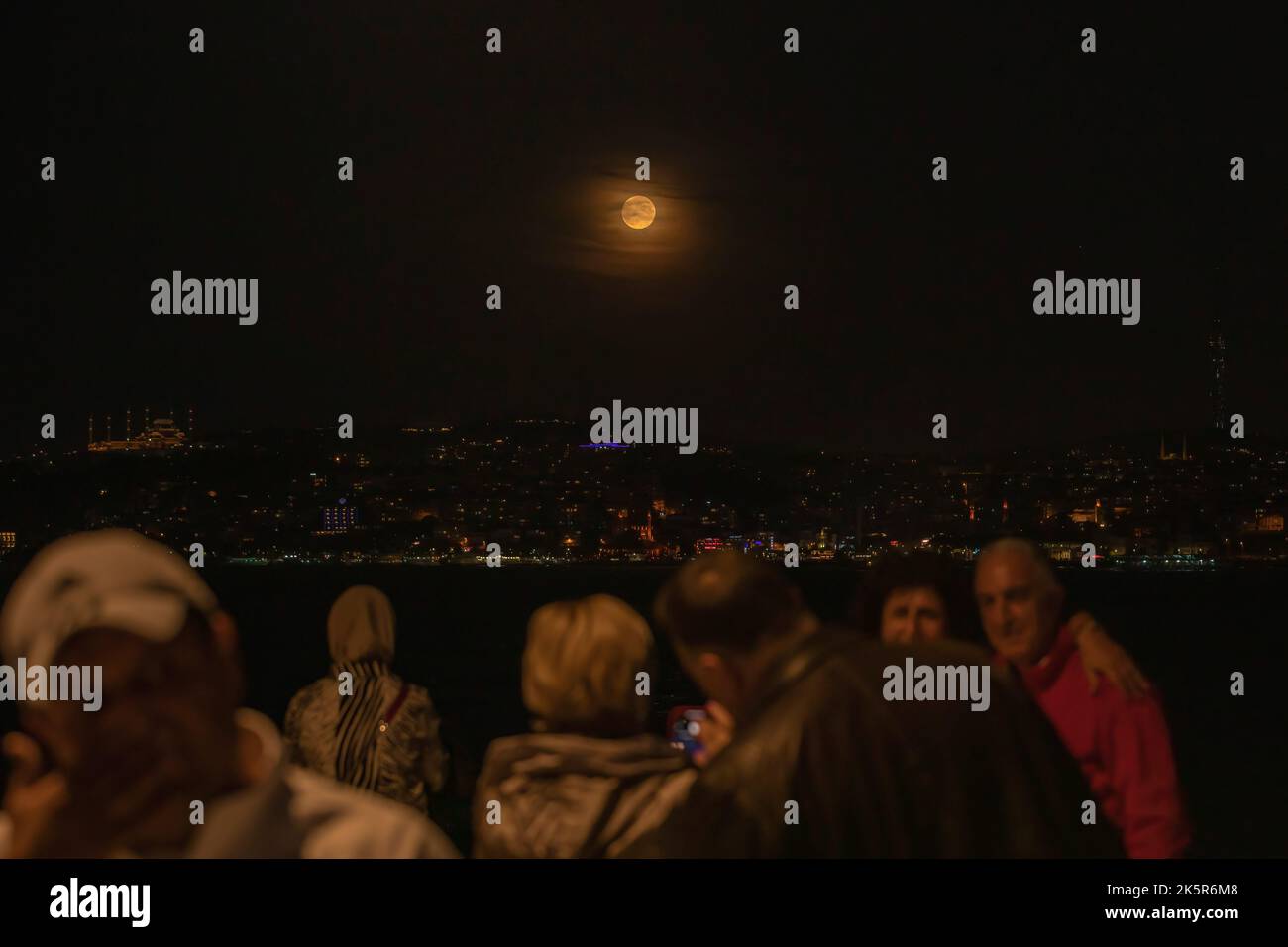 People looking at the full moon appearing in the sky take photos with ...