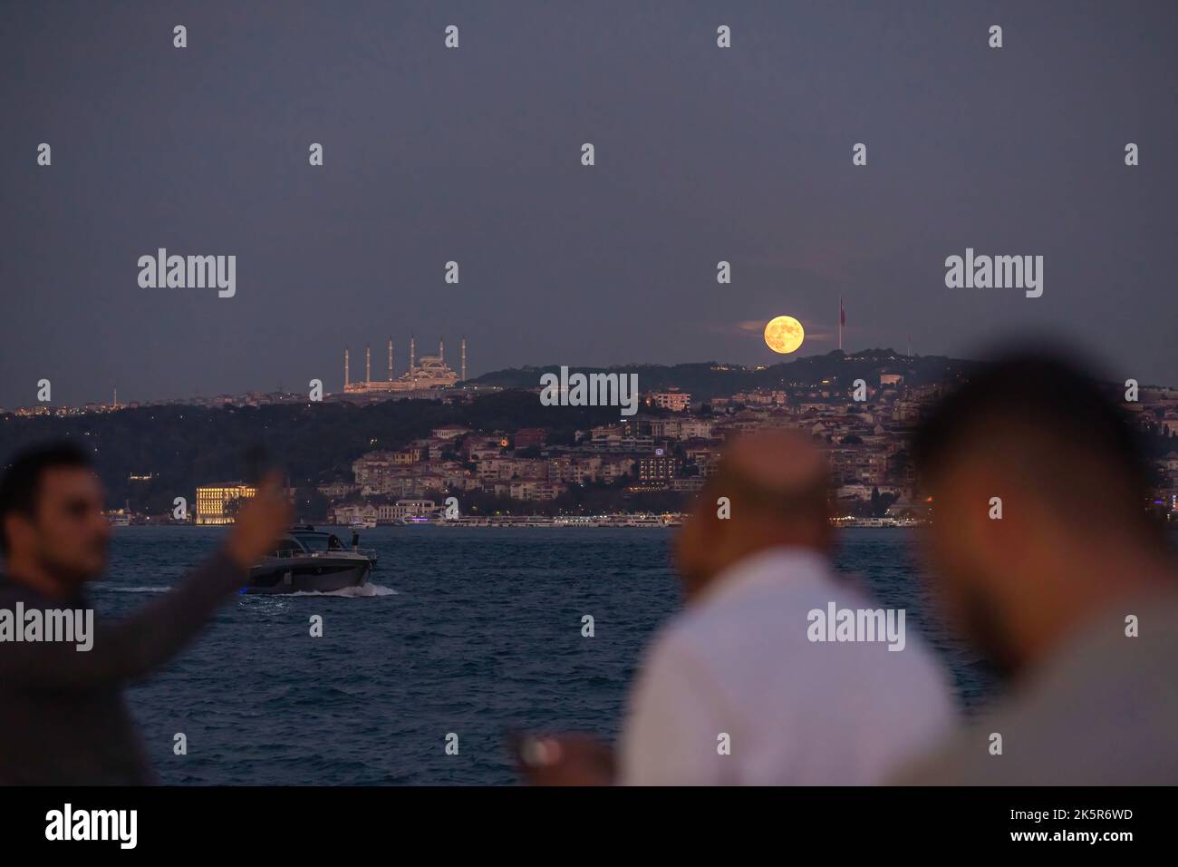 People looking at the full moon appearing in the sky take photos with ...