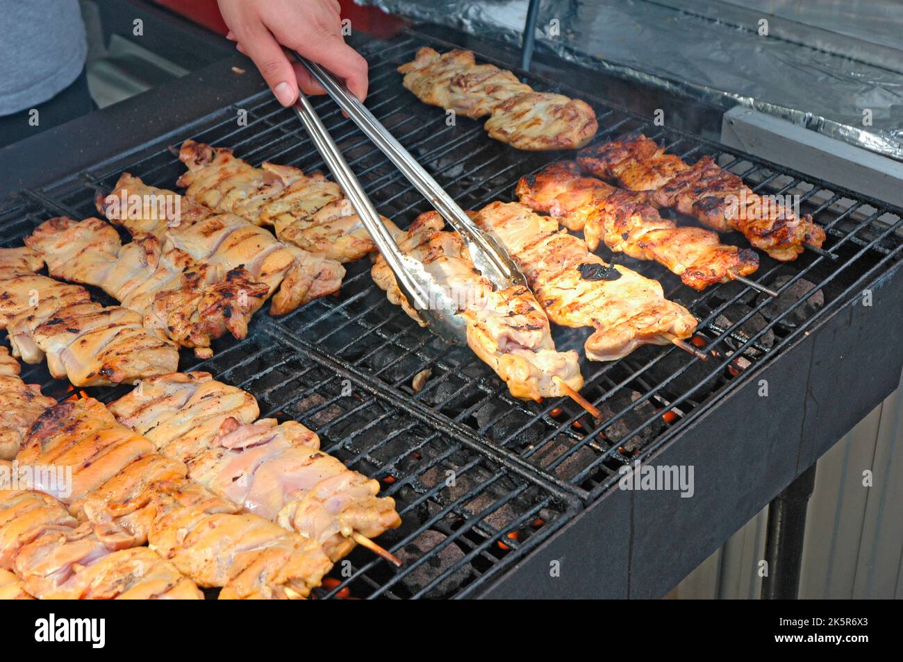 Grilling links and chicken and onions and potato cakes on open pit ...