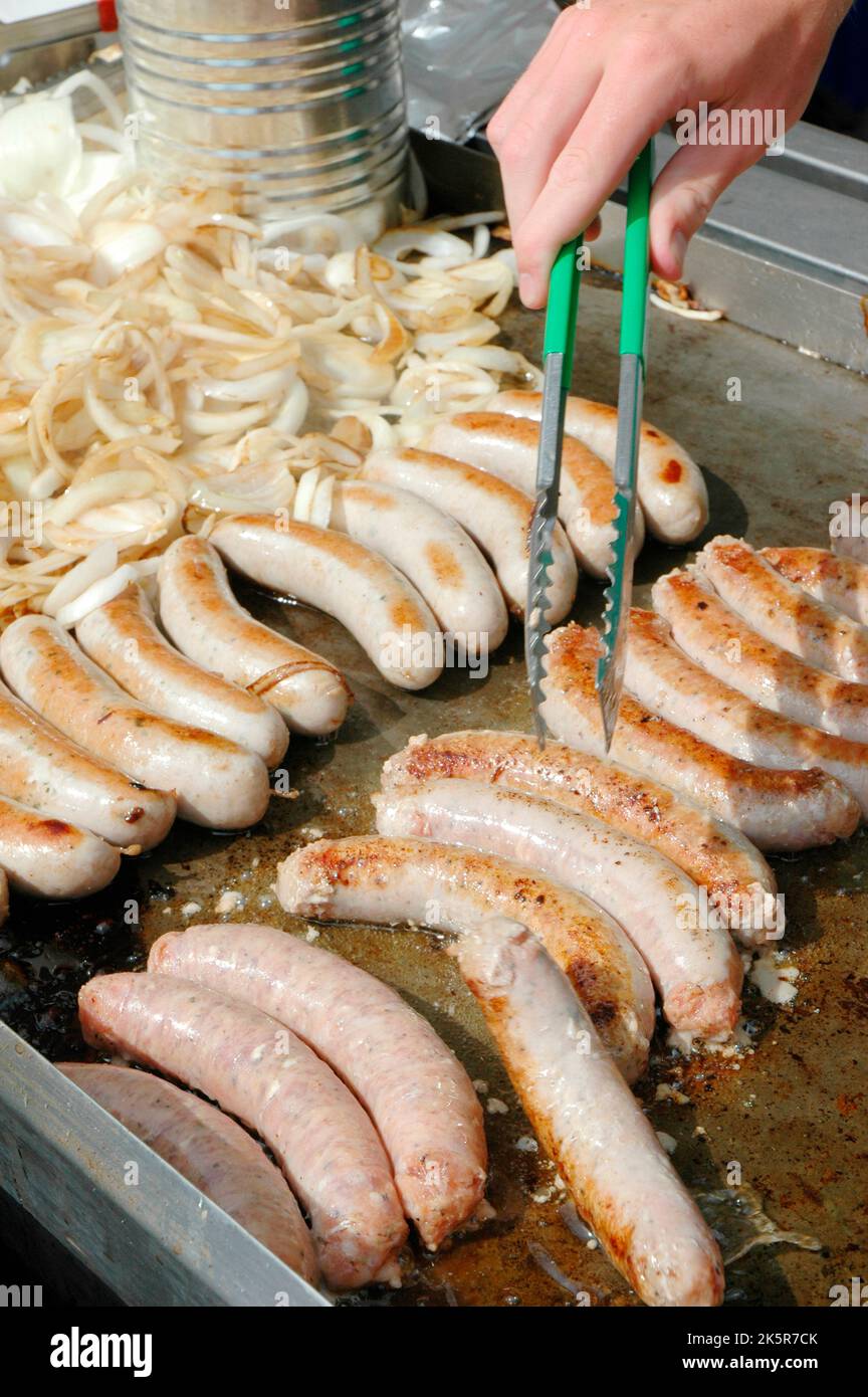 Grilling links and chicken and onions and potato cakes on open pit ...
