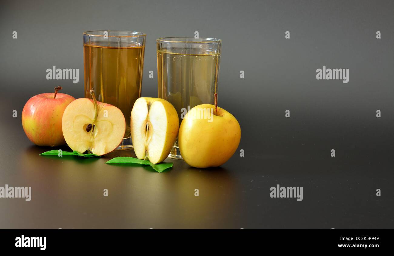 Two tall glasses with a fruit drain on a black background, next to ...