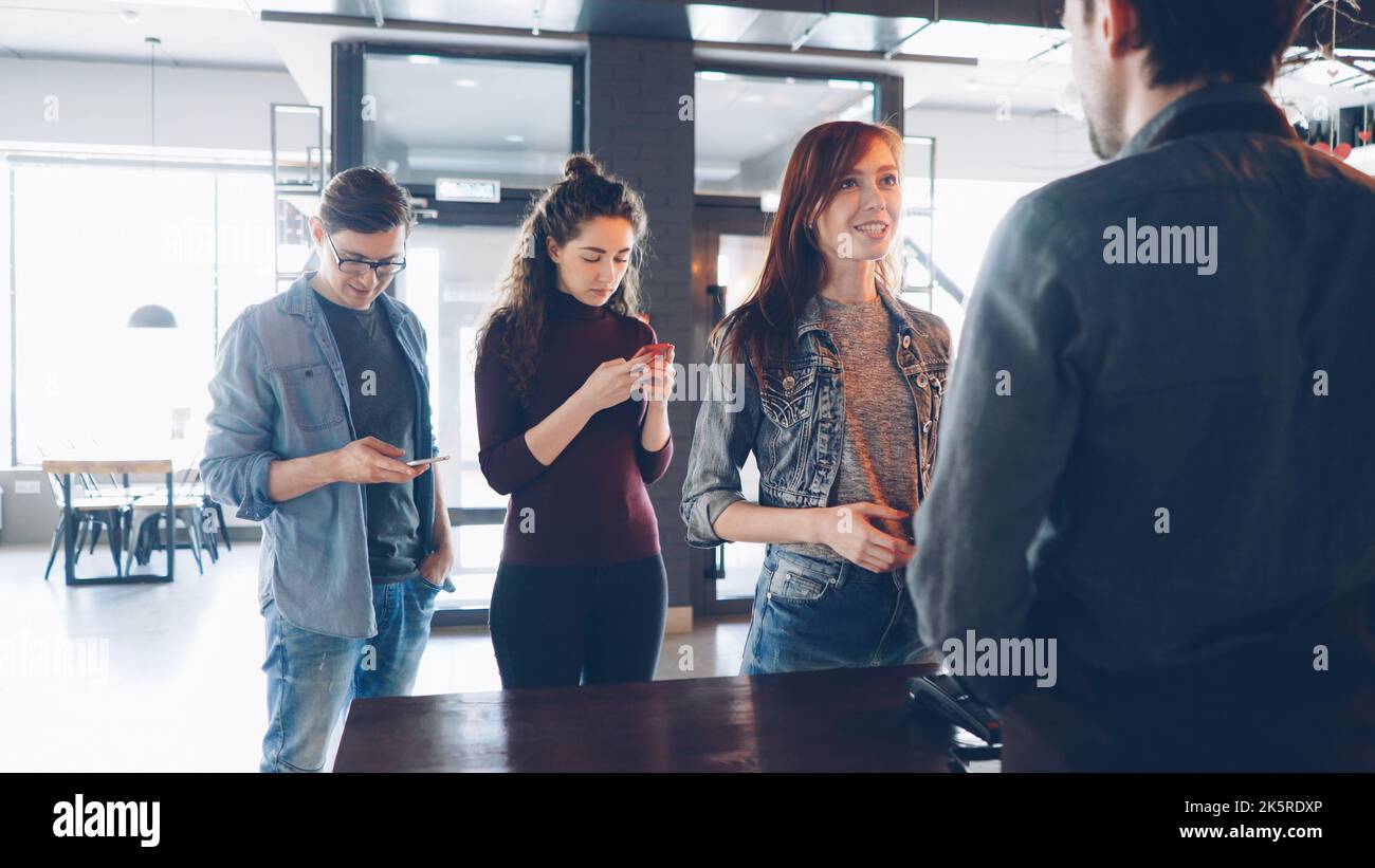 Queue of cheerful young people standing in coffee-house in the morning ...
