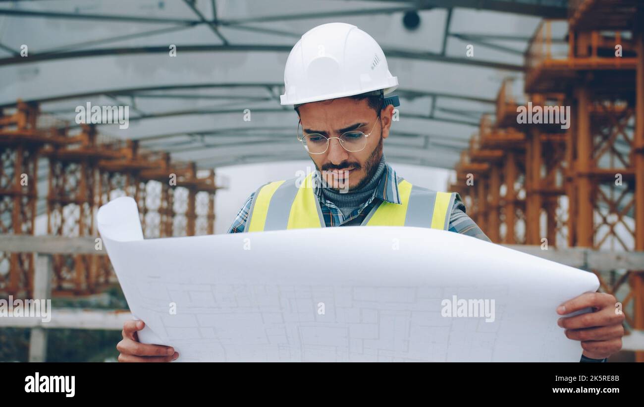 Serious Arab guy engineer is checking construction plan and looking ...