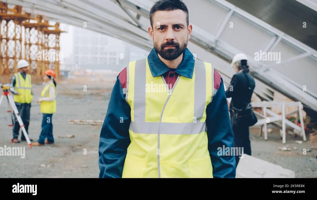 Portrait of construction employee wearing uniform standing outdoors in ...