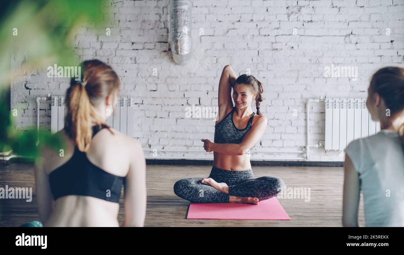 Professional friendly yoga teacher is demonstrating arm locks in cow ...