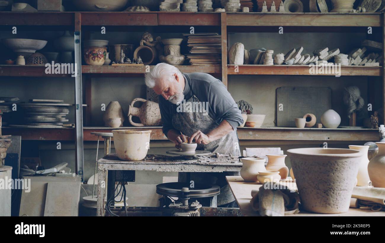Experienced male ceramist is creating utensils from clay on potter's ...