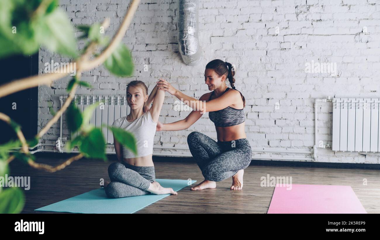 Pretty blond female yoga student is learning arm twists in cow face ...