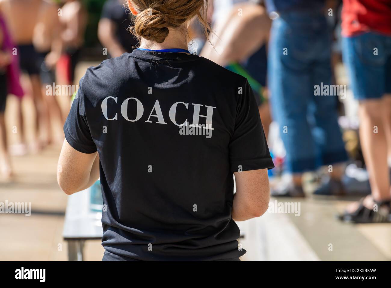 Back View Of Swimming Coaches Wearing Coach Shirt Working At An