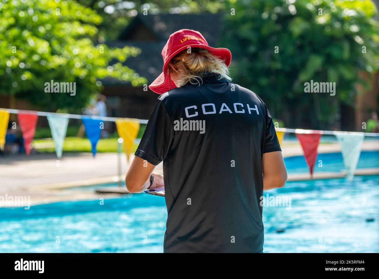 Back View Of Swimming Coaches Wearing Coach Shirt Working At An