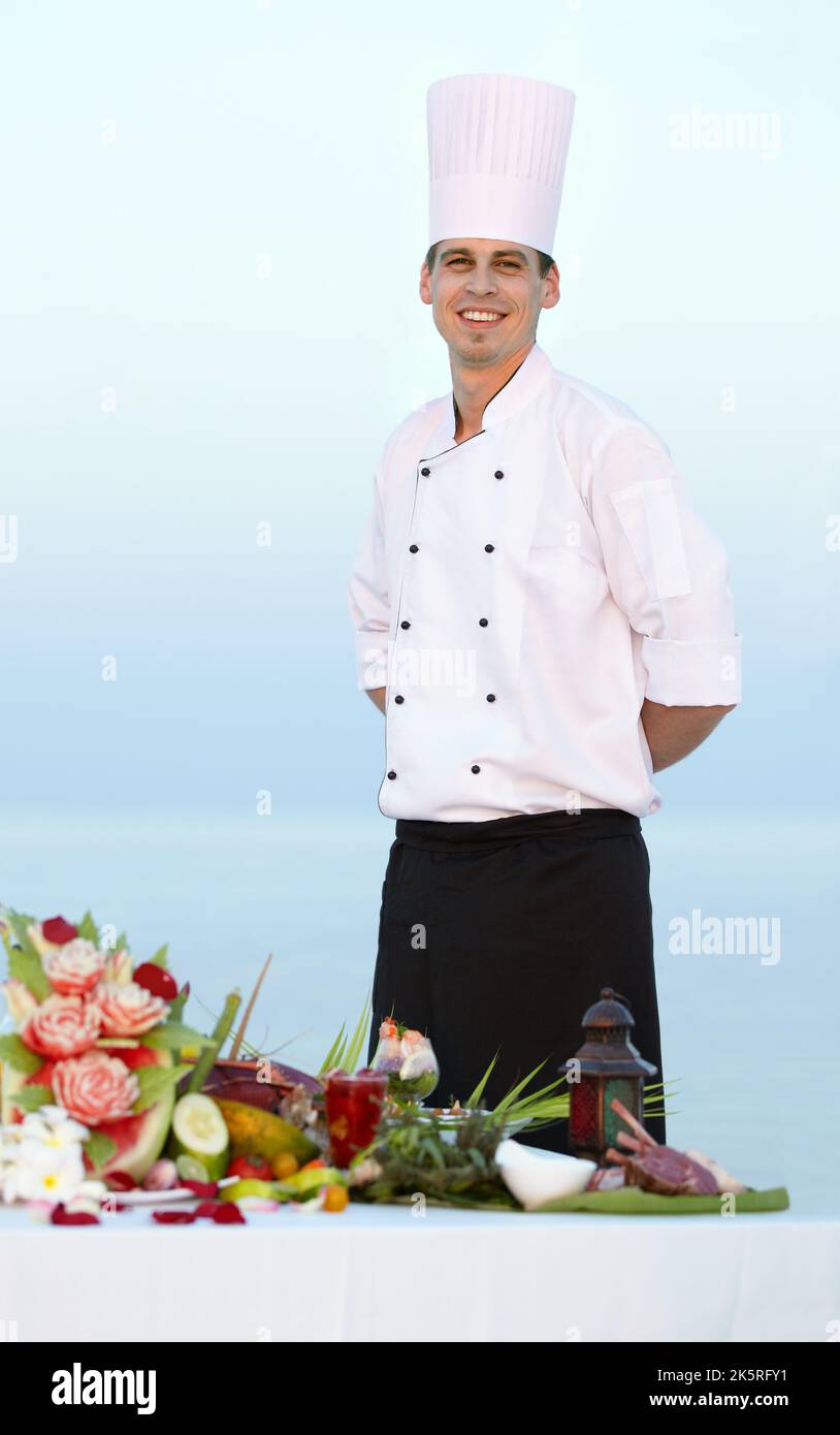 A culinary genius. Smiling young chef in uniform standing proudly over ...