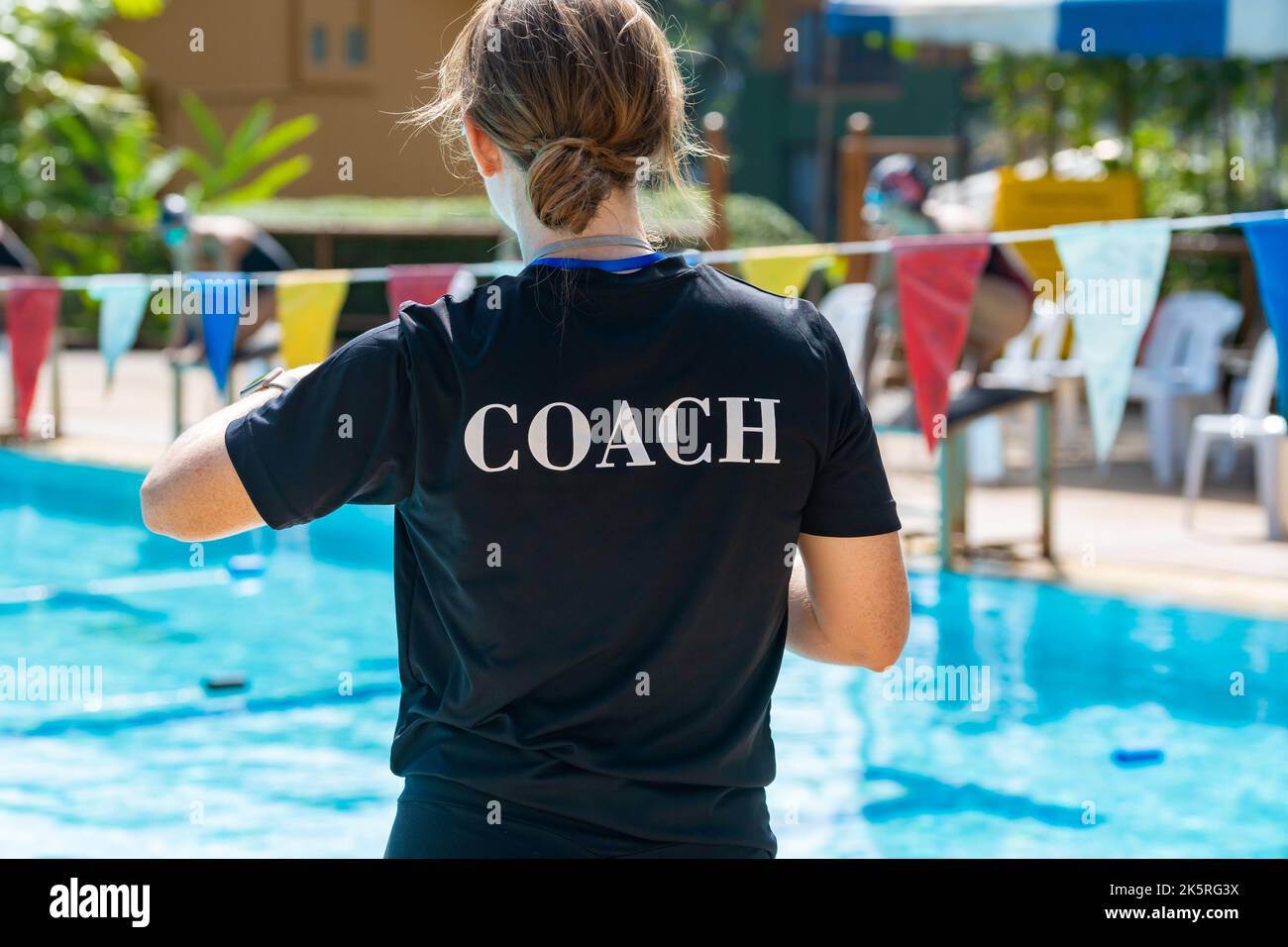 Back View Of Female Swimming Coaches Wearing Coach Shirt Working At