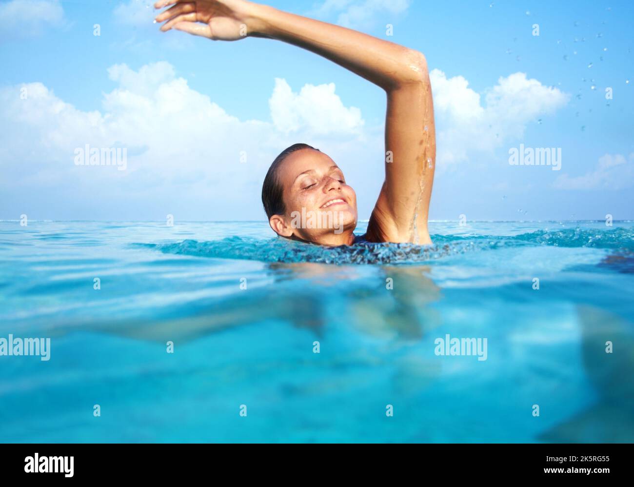 Alive and invigorated. a beautiful young woman swimming in blue ocean ...