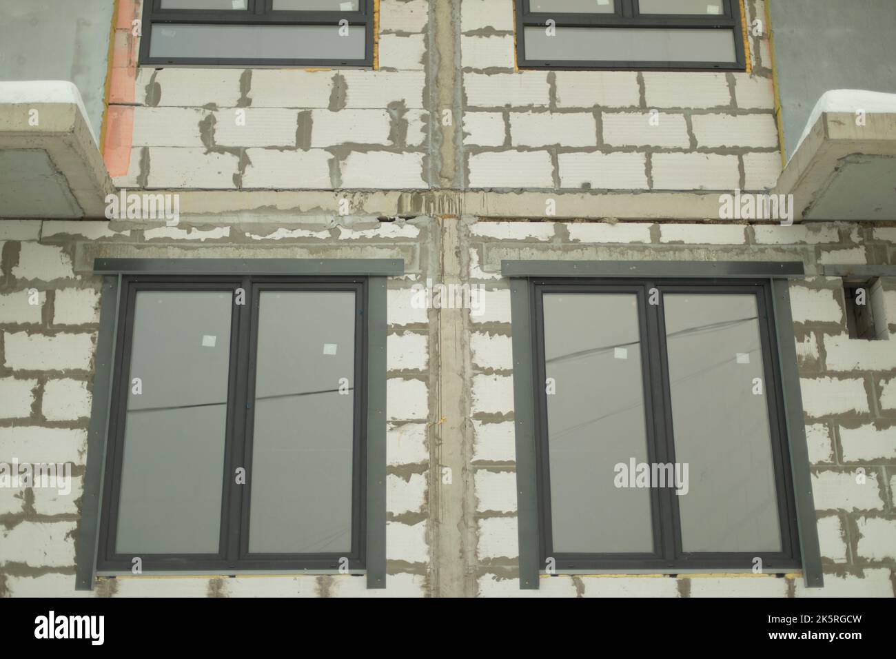 Windows in building. Unfinished house. New window frames outside house ...