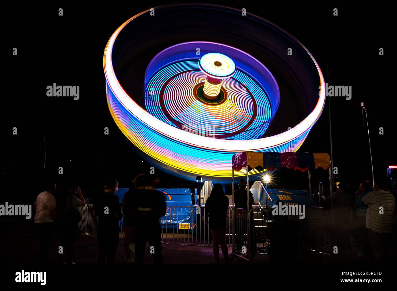 Several people near the high-speed spinning attraction with colorful ...