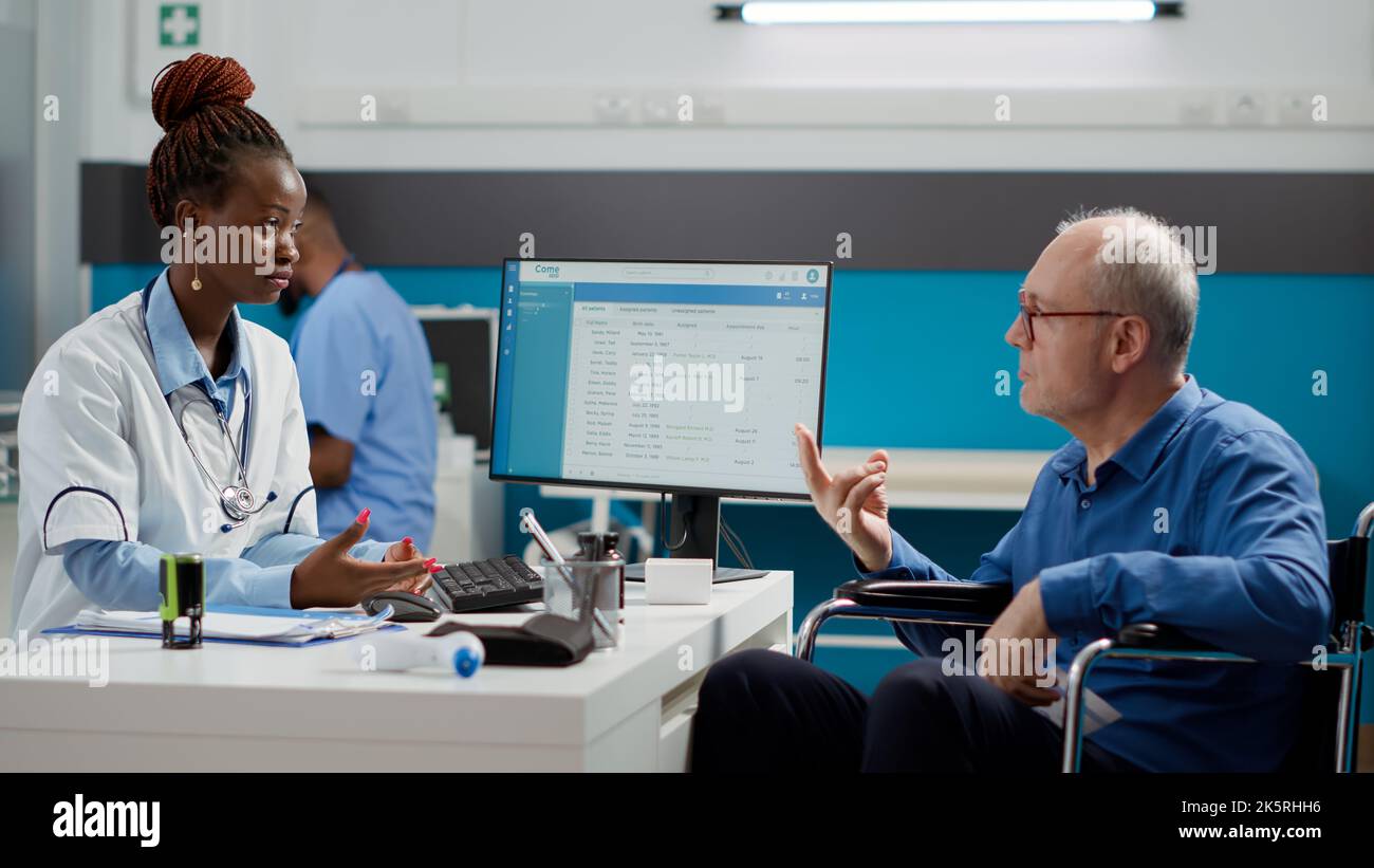 African american medic giving prescription paper to wheelchair user ...