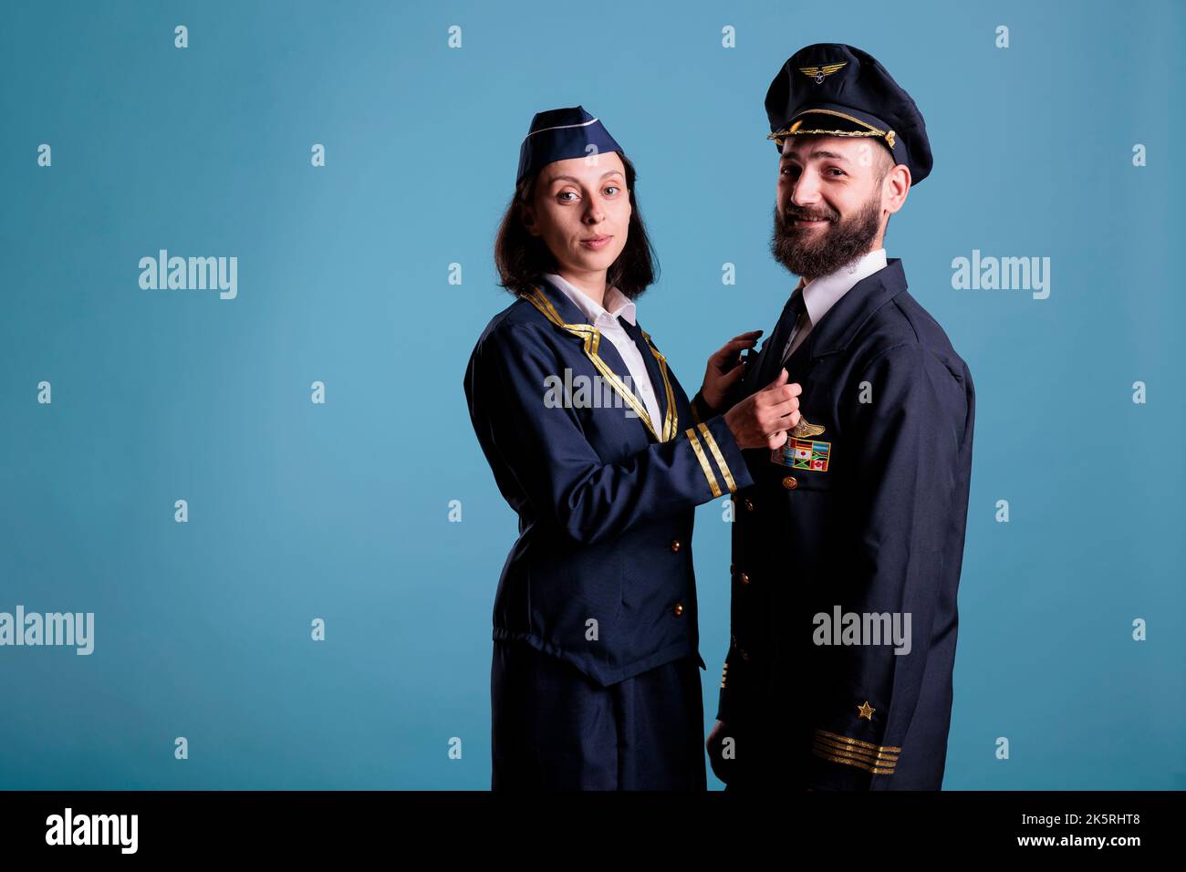 Smiling airplane pilot and flight attendant couple in uniform looking ...