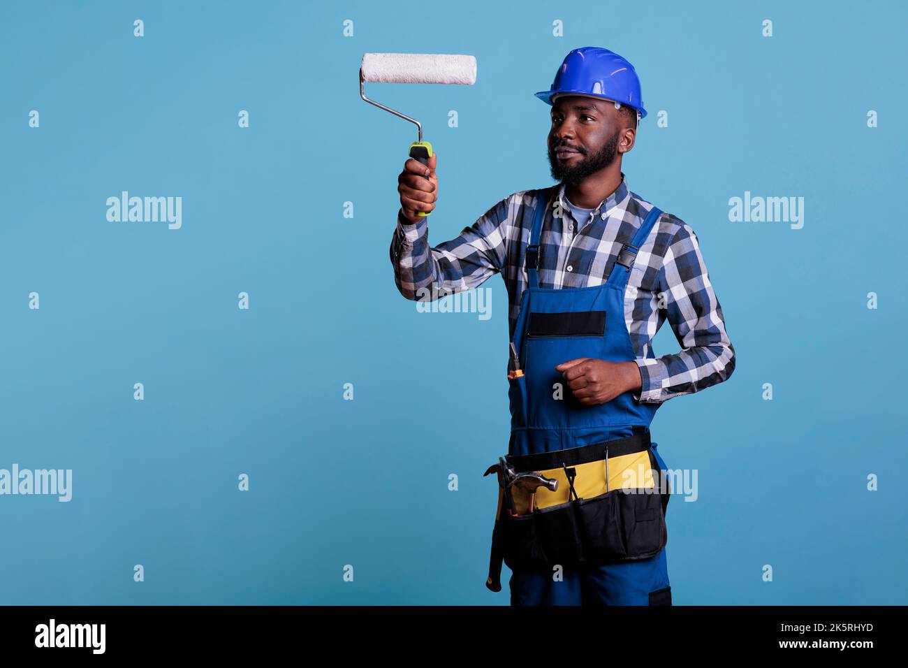 Painter focused on work holding professional roller to paint an ...