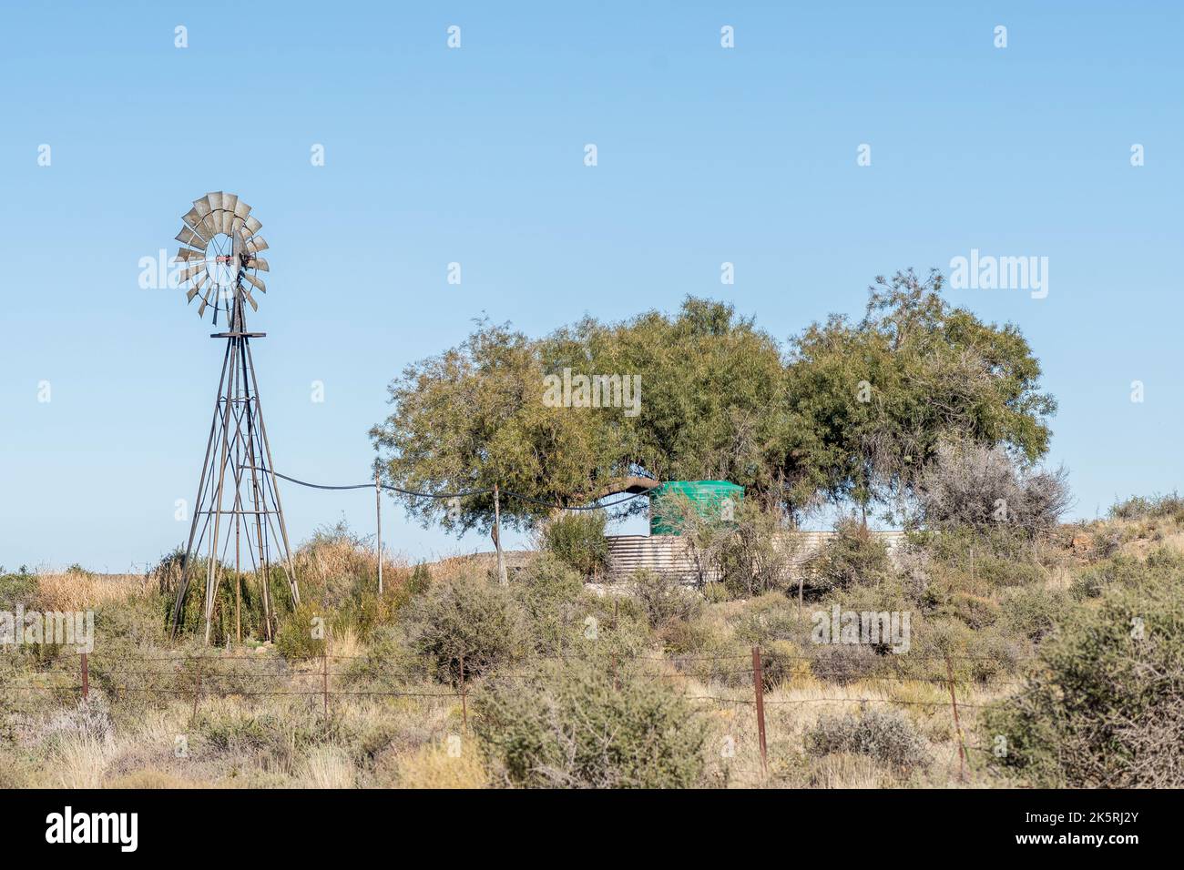 A windmill and a watertank inside an old reservoir on the road between ...