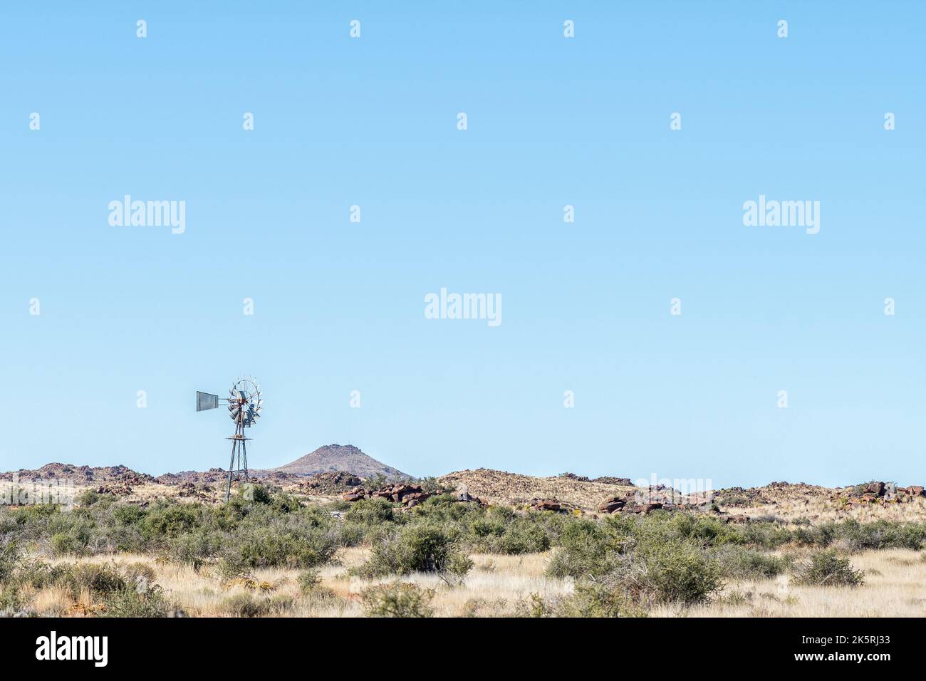 A typical Karoo landscape, with a windmill and hills, on road R356 ...