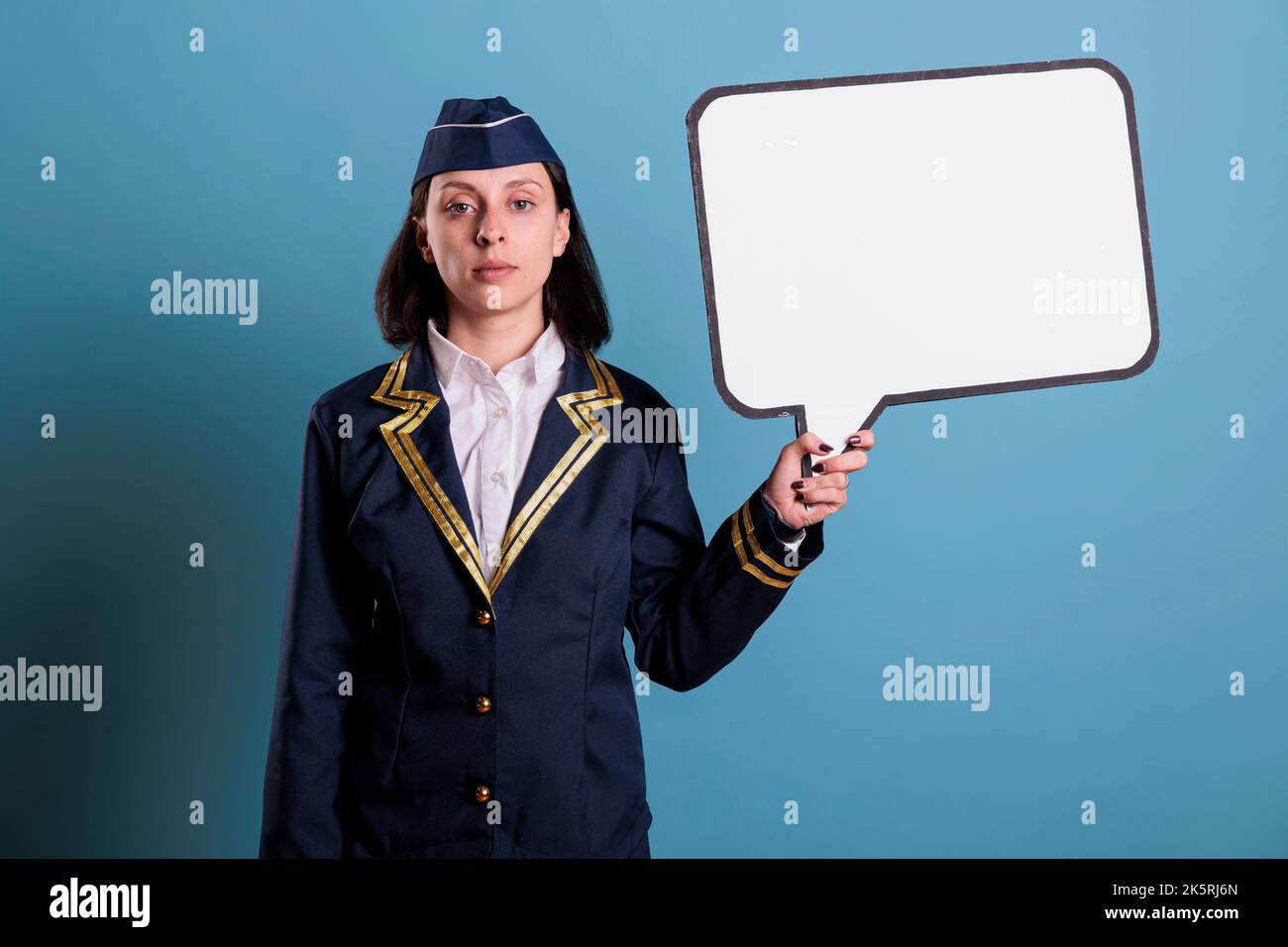 Smiling stewardess holding white blank speech bubble, flight attendant ...