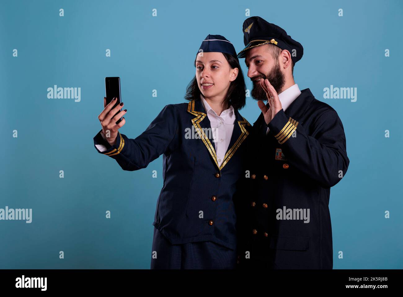 Smiling pilot using and flight attendant talking on smartphone ...