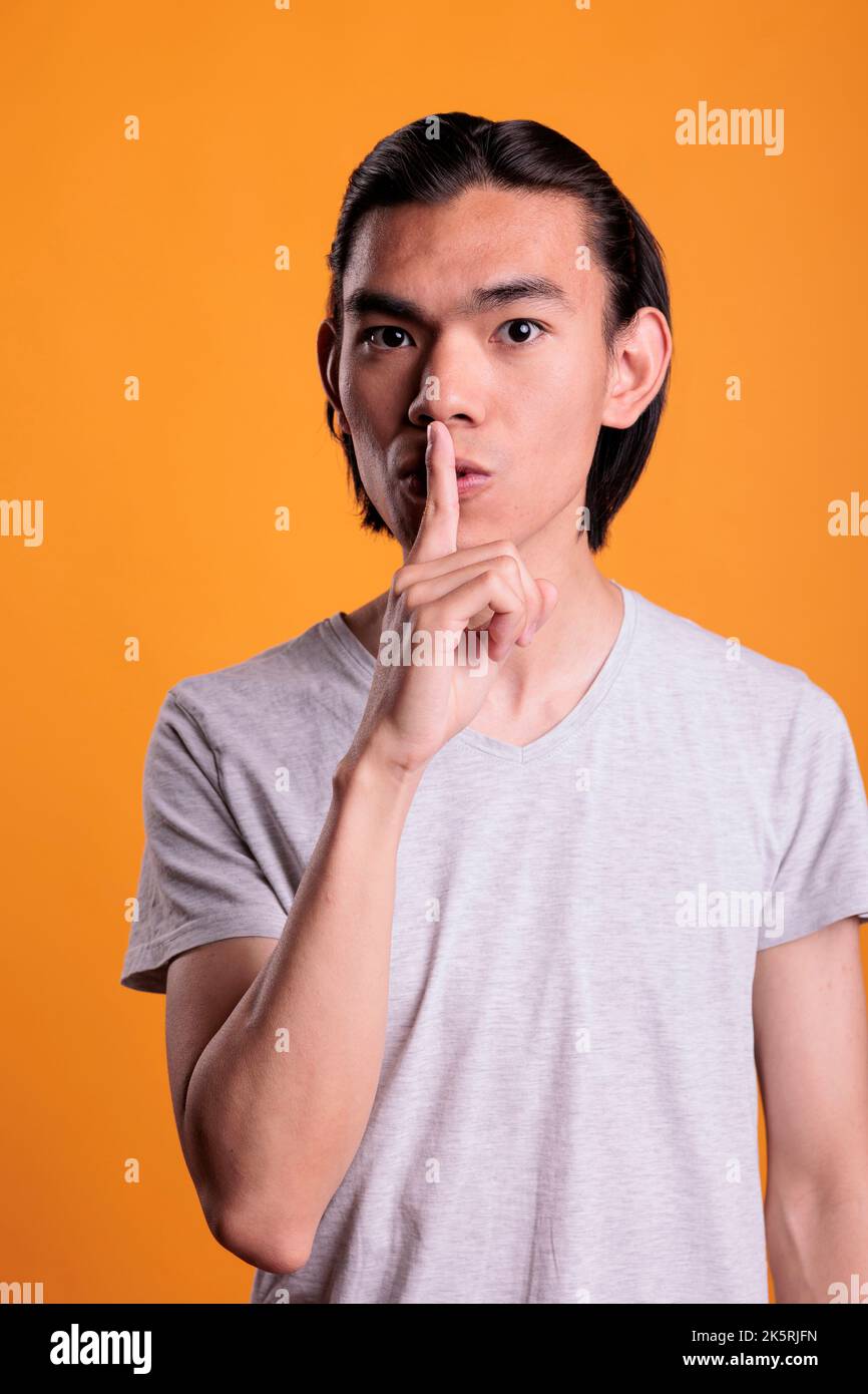 Young asian man showing silence gesture, making tsss sign. Serious ...