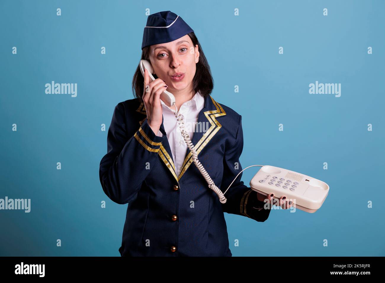 Stewardess talking on landline phone, holding telephone, having remote ...