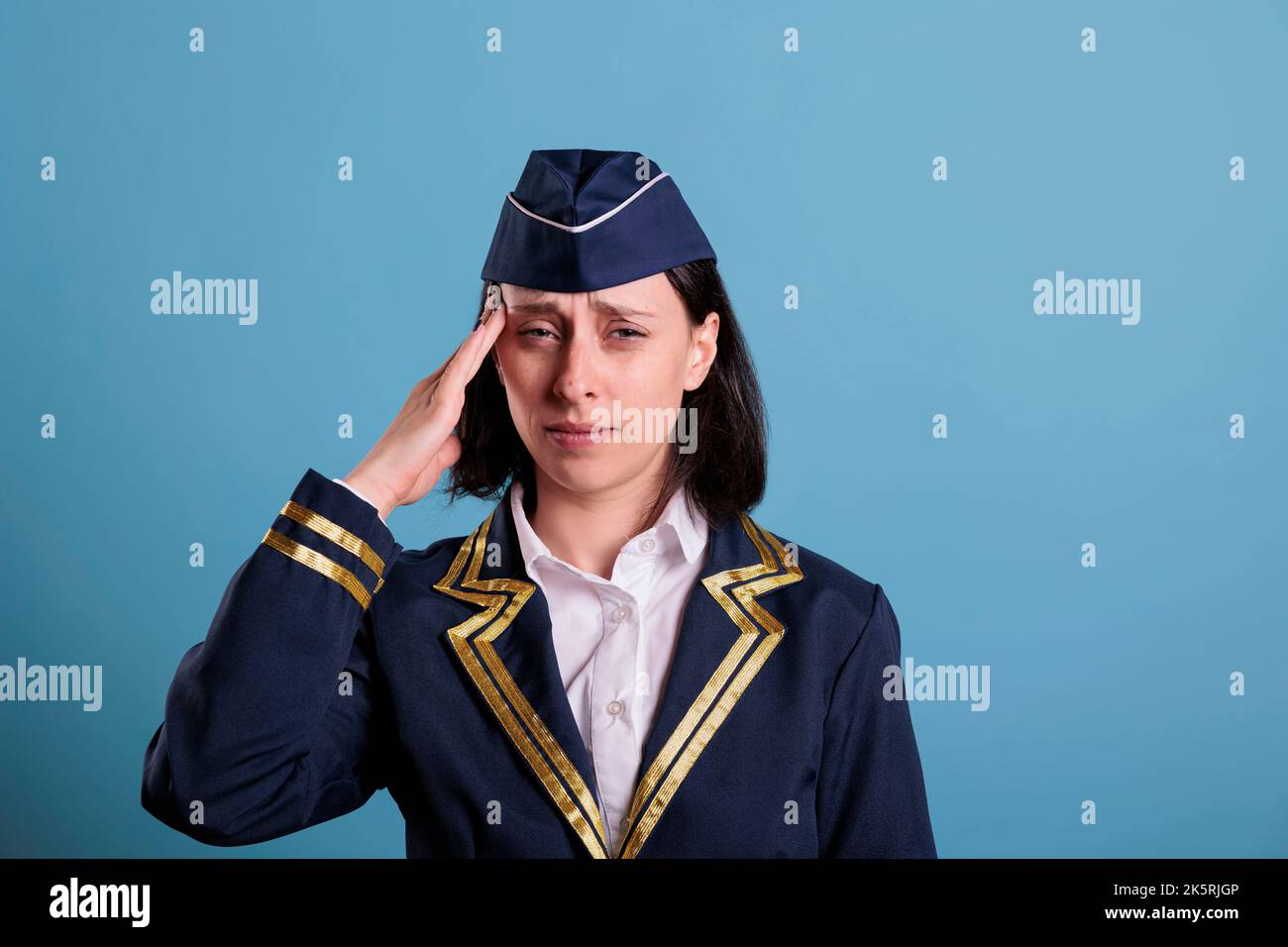 Flight attendant having migraine symptom, touching temples with fingers ...