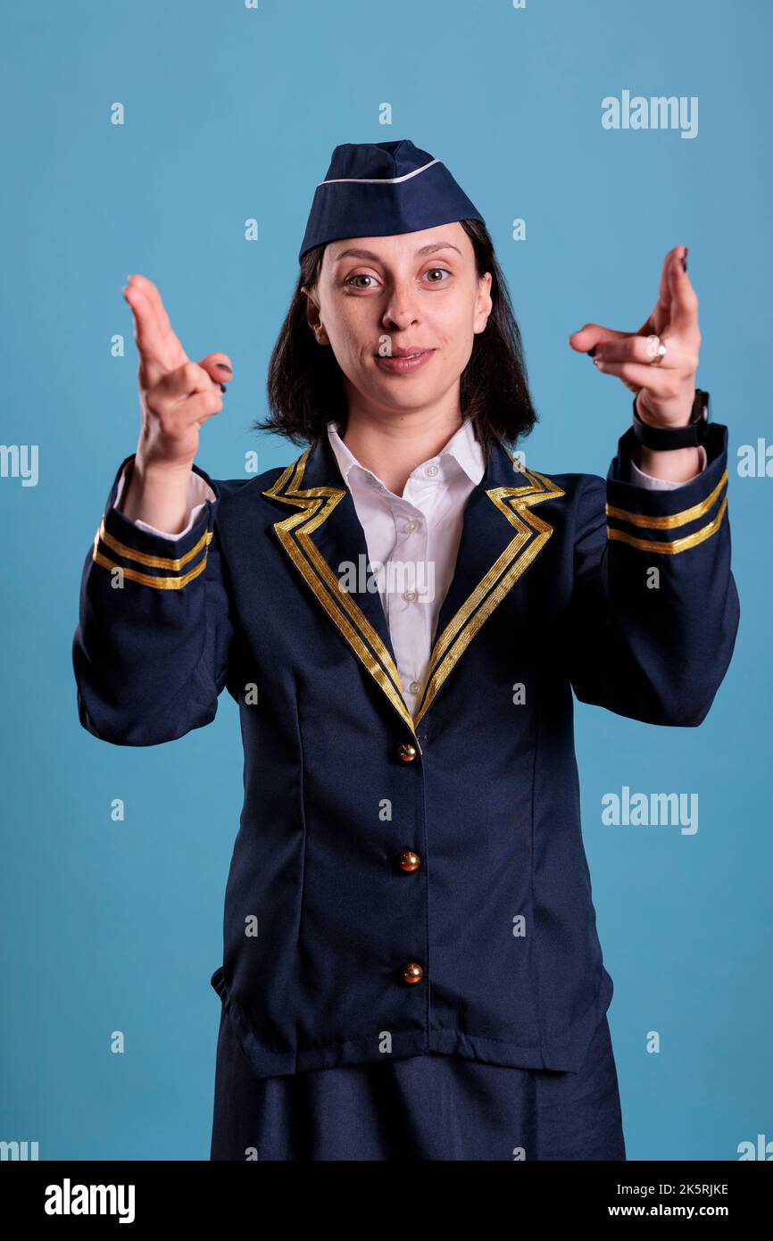 Smiling flight attendant showing emergency exit on plane board, safety ...