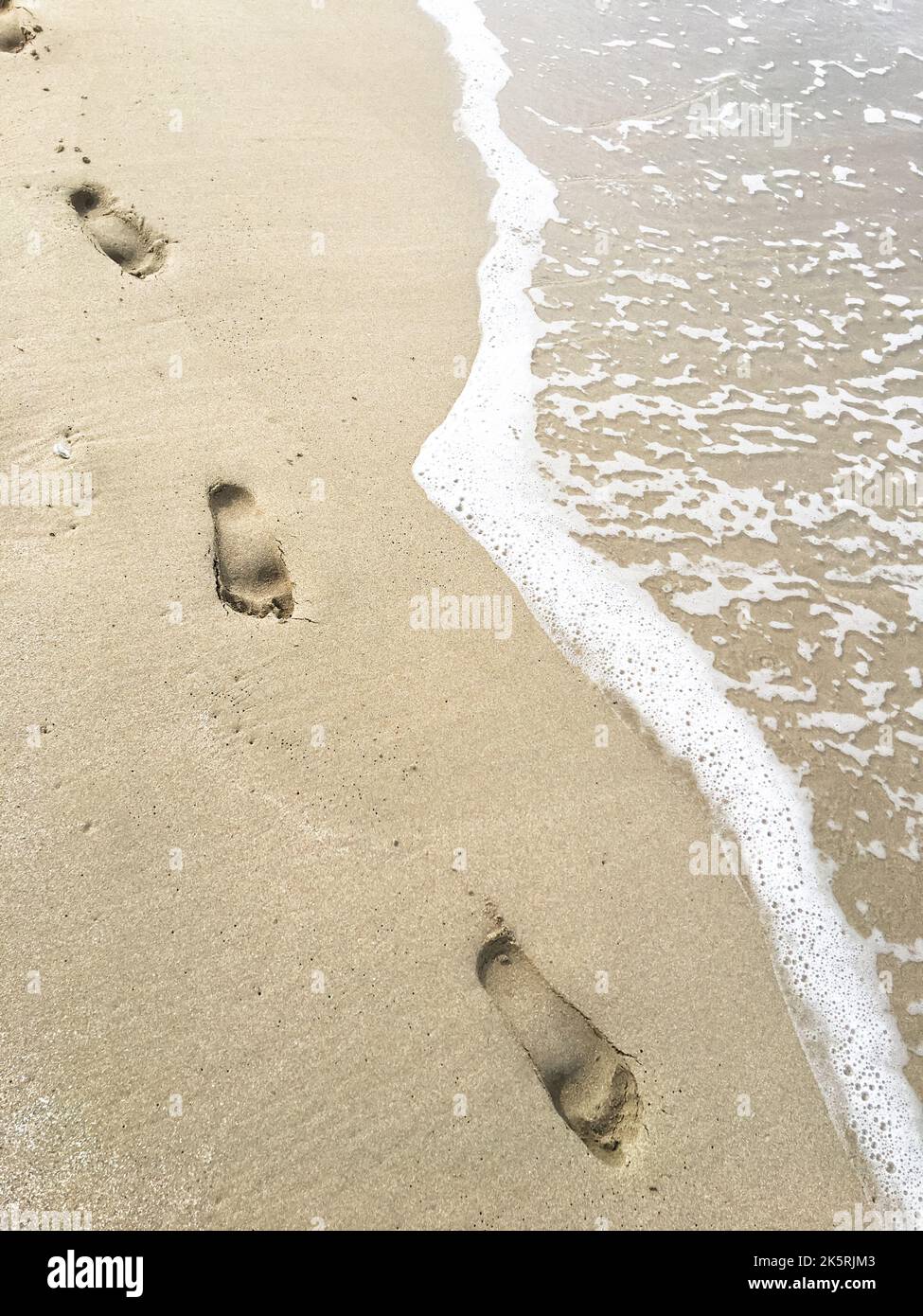 Human footprints in the sand and sea foam. Beach backgrounds. Walk care ...