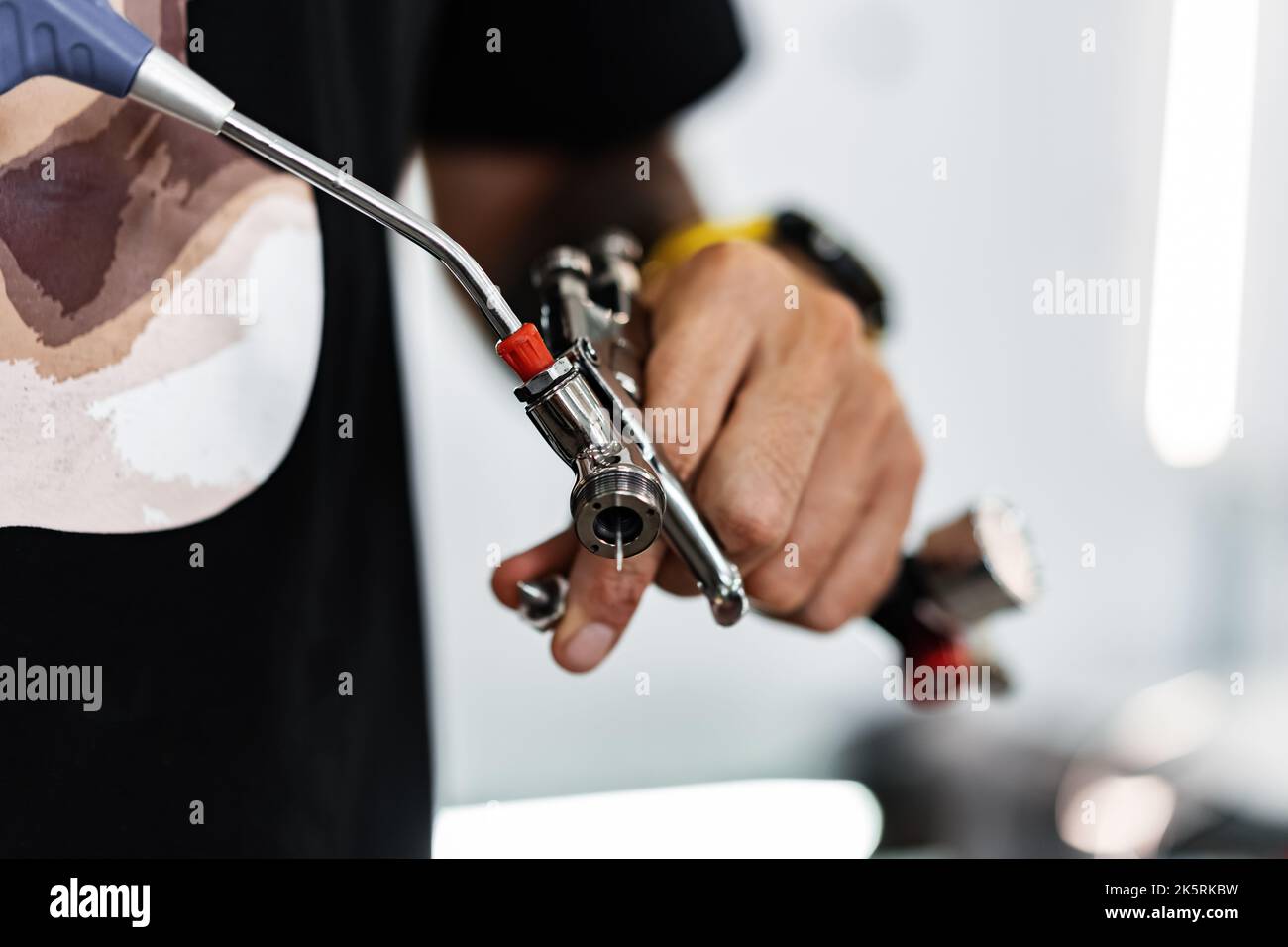 Paint spray gun in the hands of a painter close up Stock Photo - Alamy