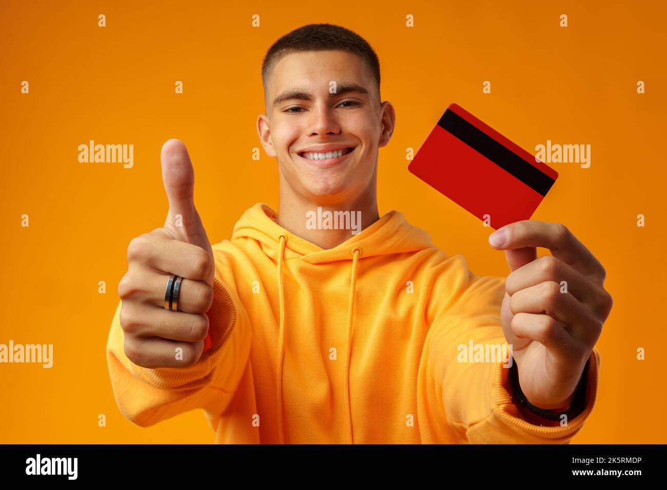 Handsome young man holding credit card on yellow color background Stock ...