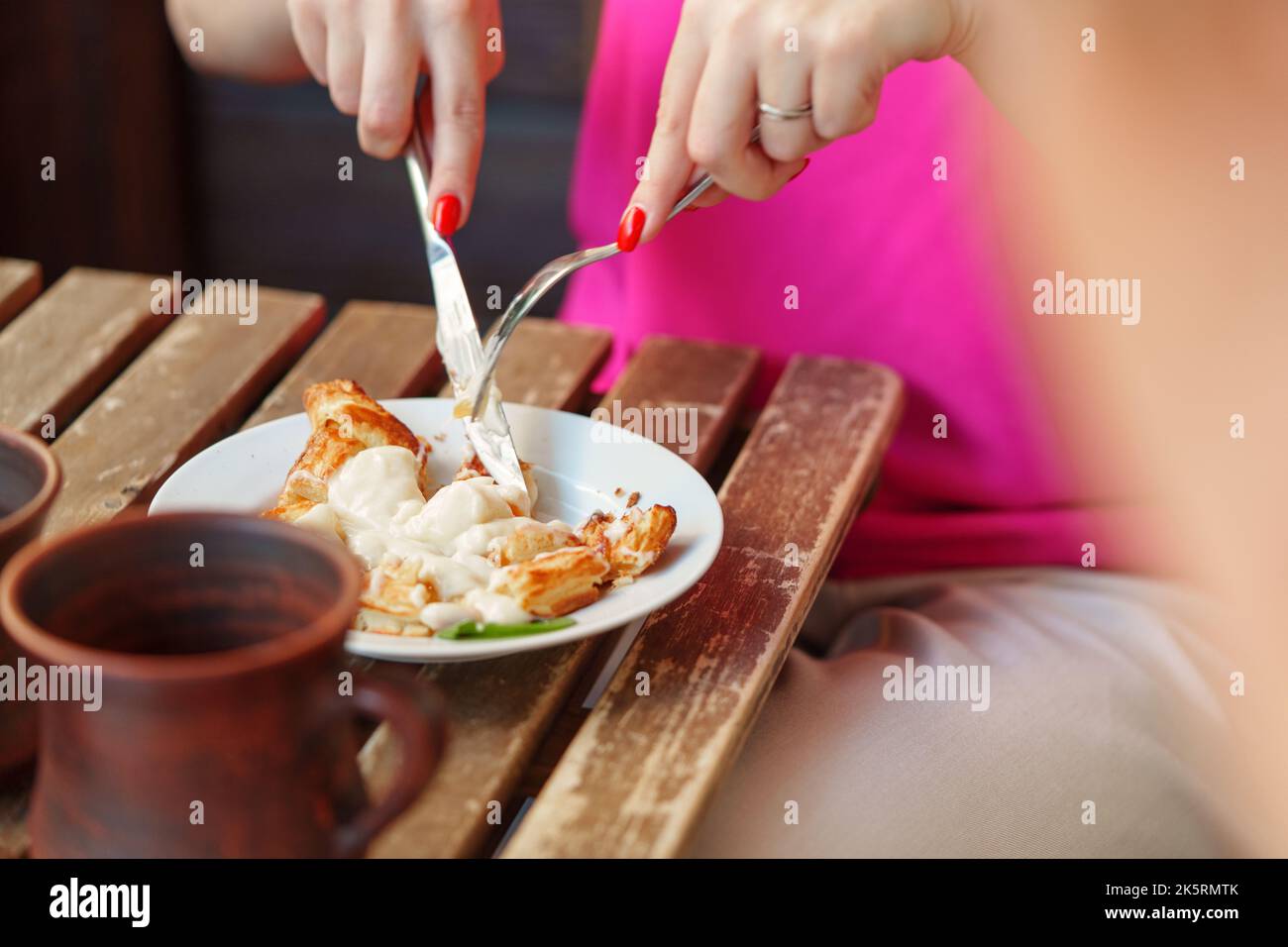 Close up of a woman in pink top eating a dessert in cafe Stock Photo ...