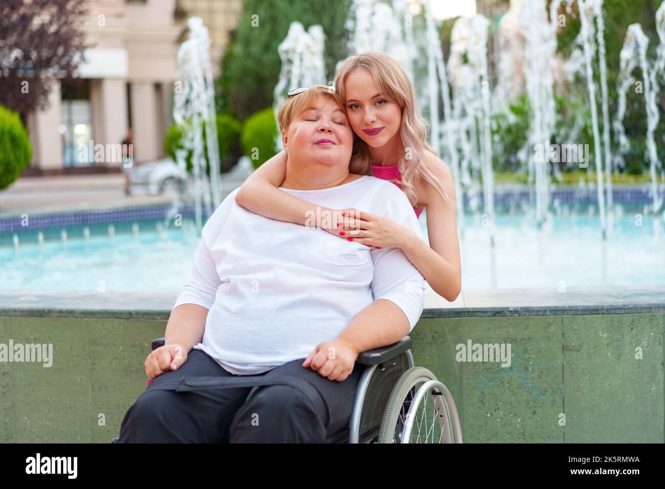 Young daughter taking care of her mother with disability sitting in ...