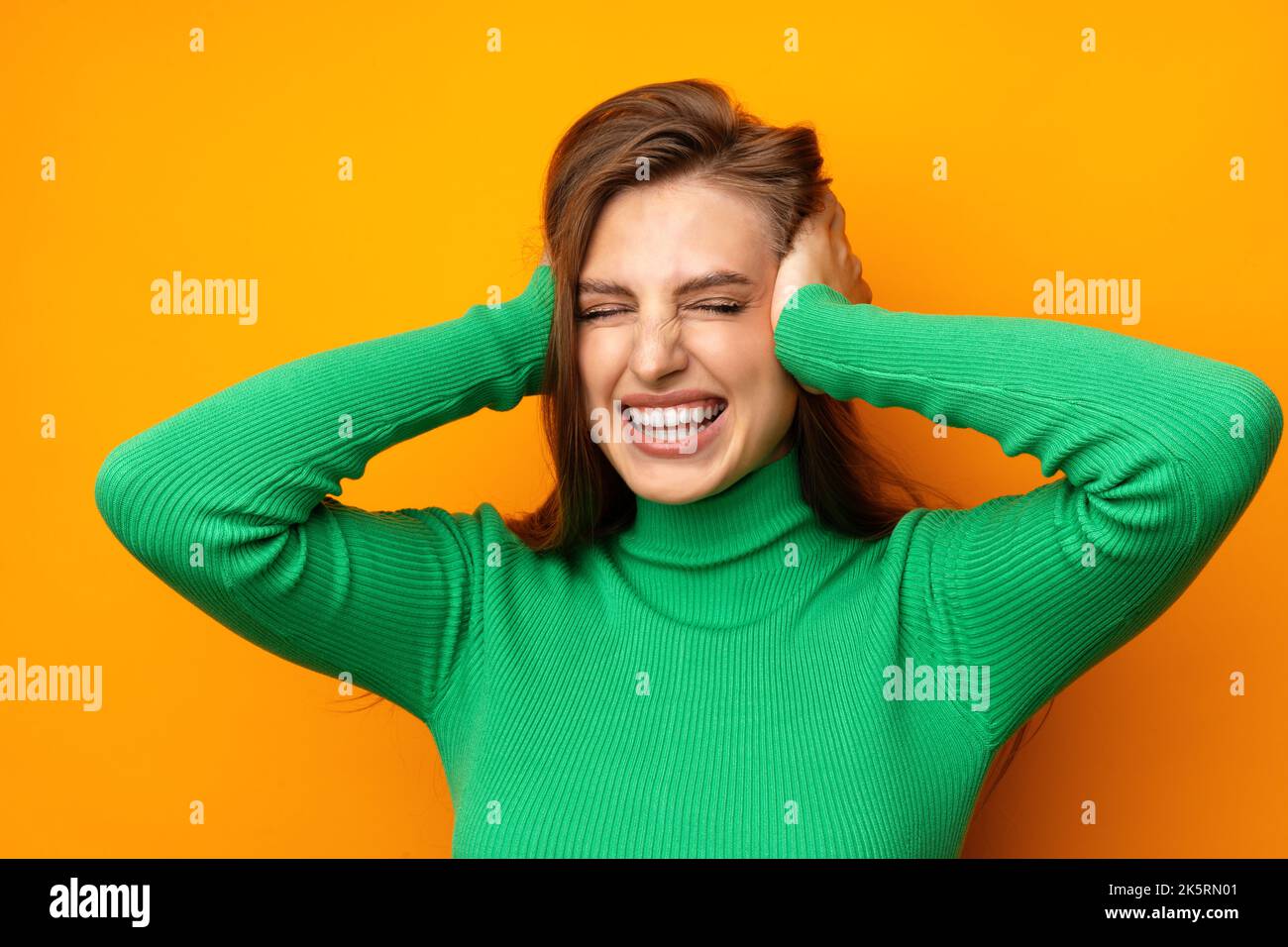 Anxious young woman holding hands on head standing frustrated against ...