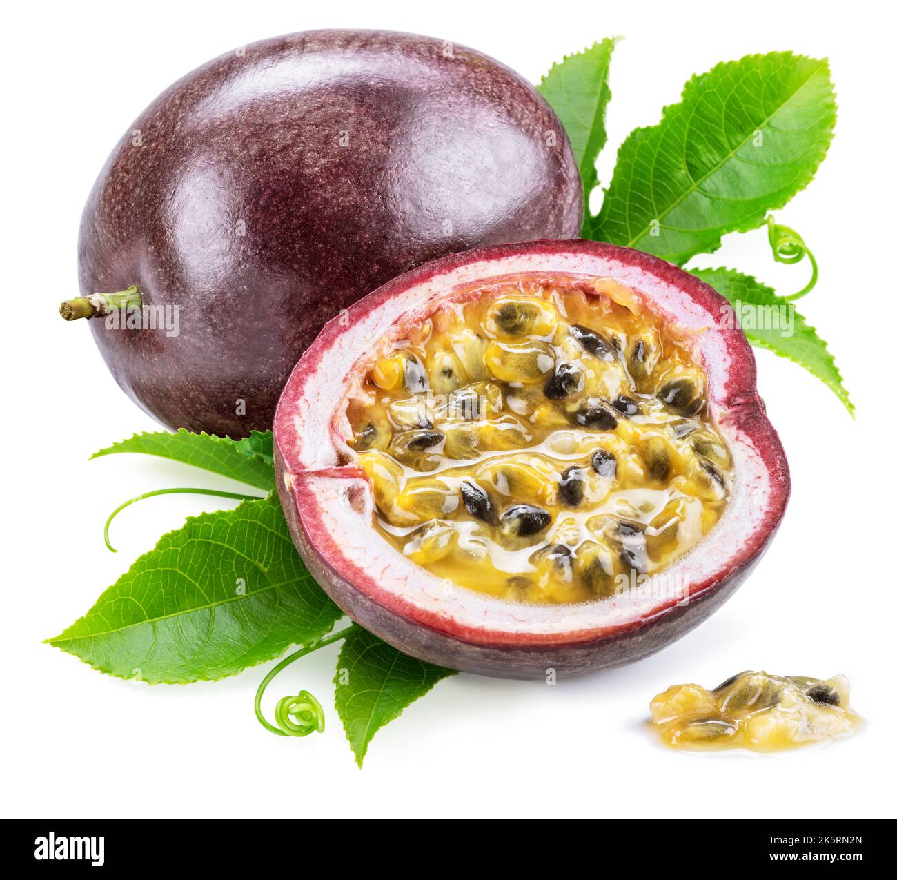 Dark purple passion fruit and half of fruit with green leaves on white ...