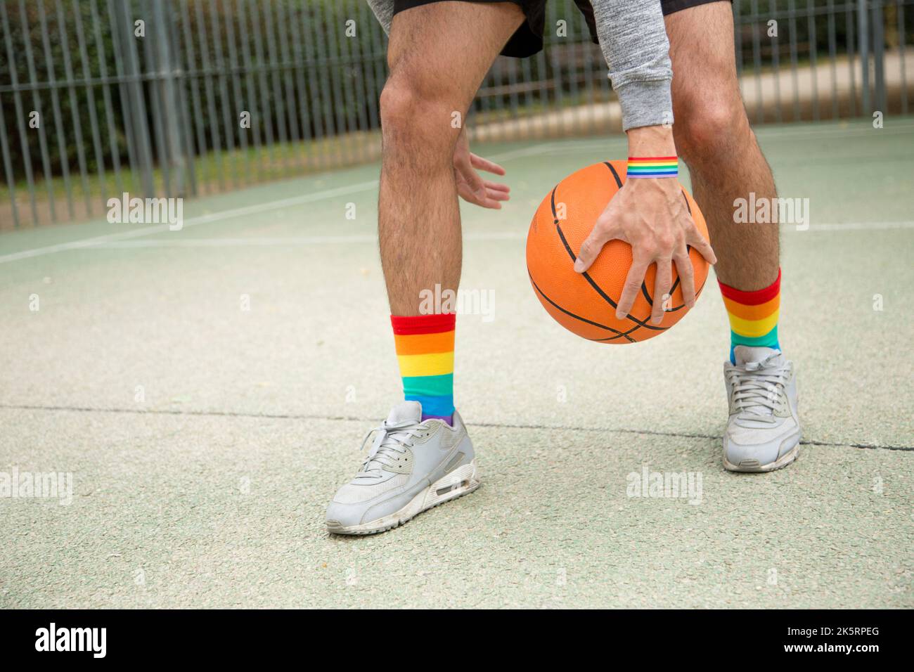 Basketball player in sneakers and rainbow socks dribbling with a ball ...