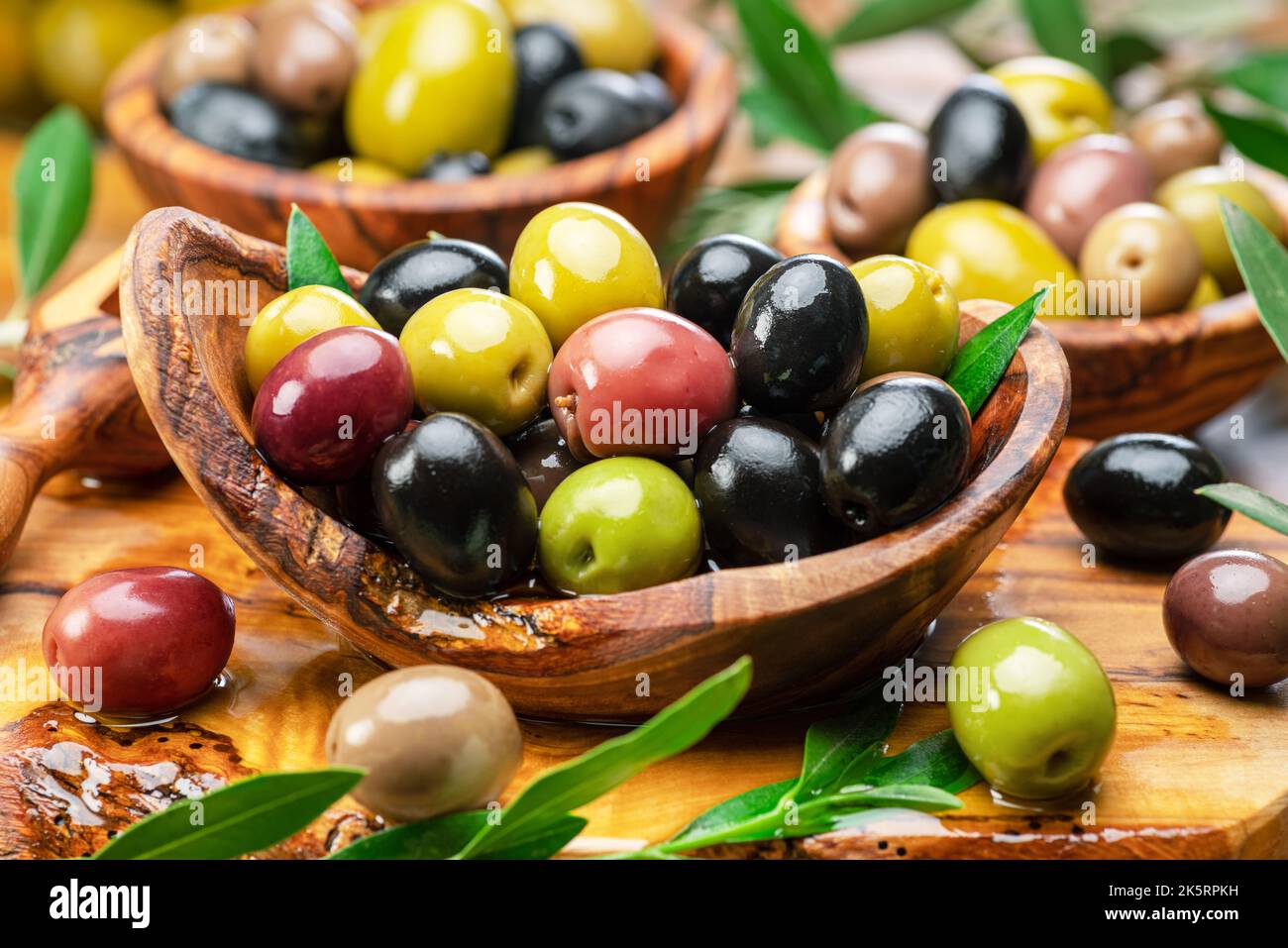 Kalamata, green and black olives in the wooden plate. Food background ...