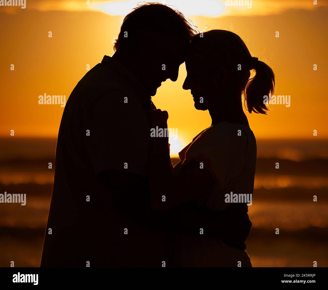 Silhouette affectionate senior couple sharing an intimate moment on the ...