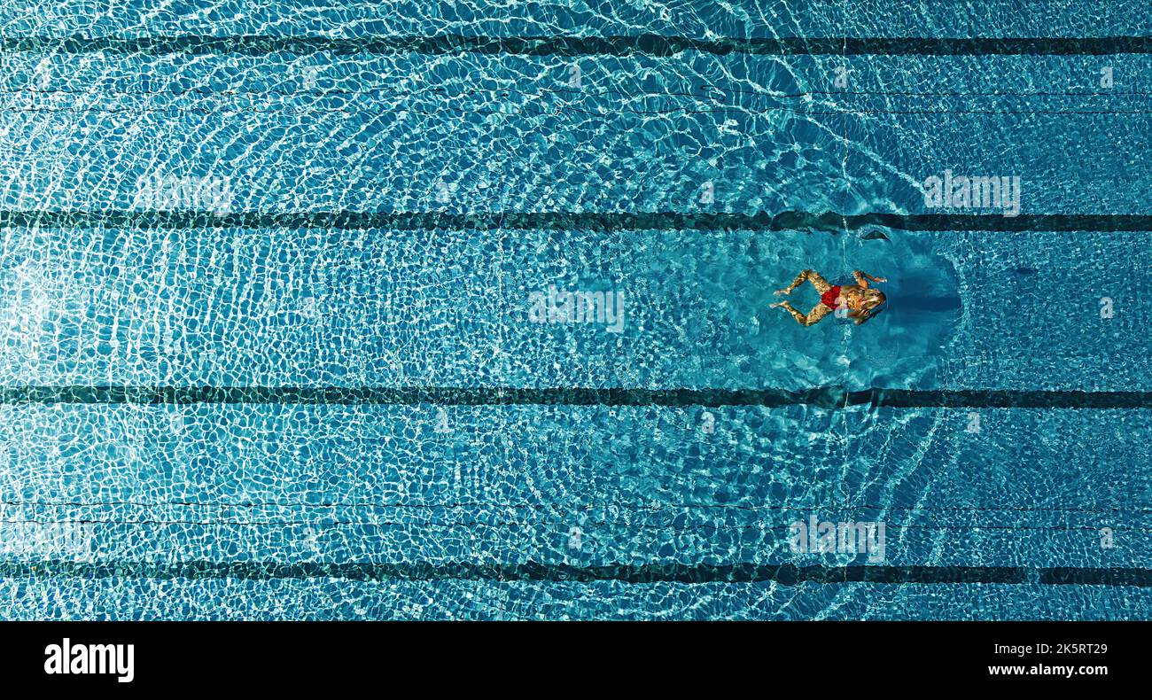 Top view of swimming pool from drone above of swimming woman in red ...