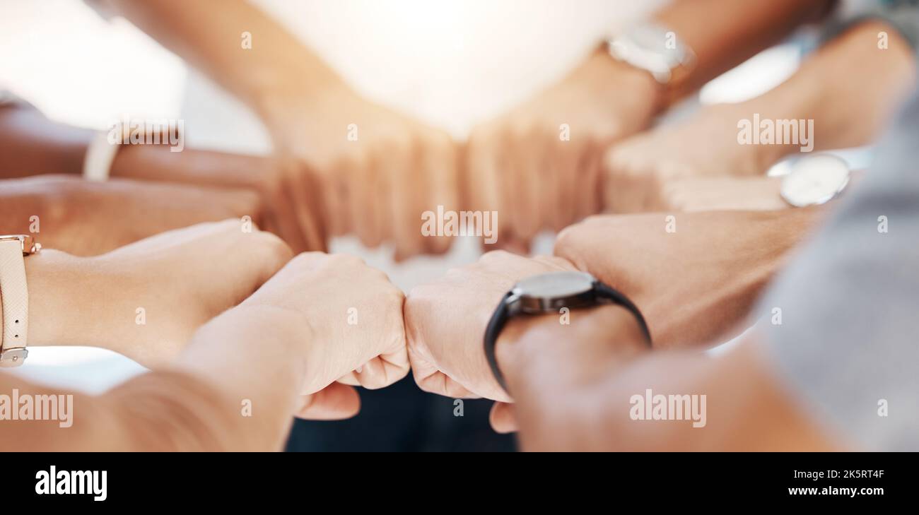 Closeup of diverse group of people making fists in a circle to express ...