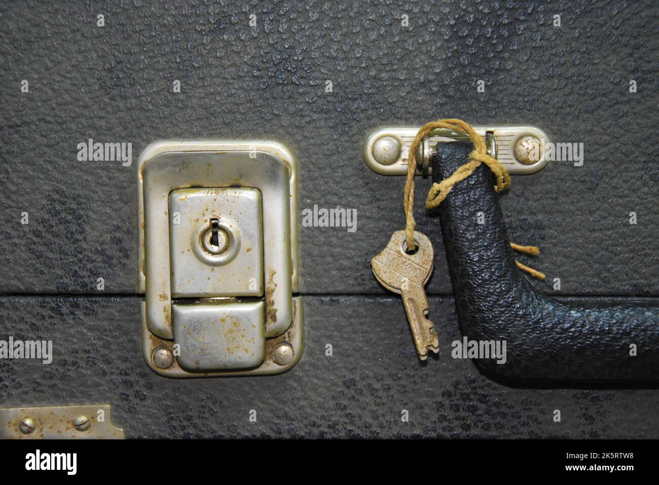 Old, Dusty part of suitcase that shows lock, key and part of a handle ...