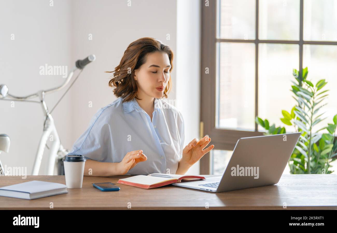 Woman working in the office and practicing deep breathing for calm and ...