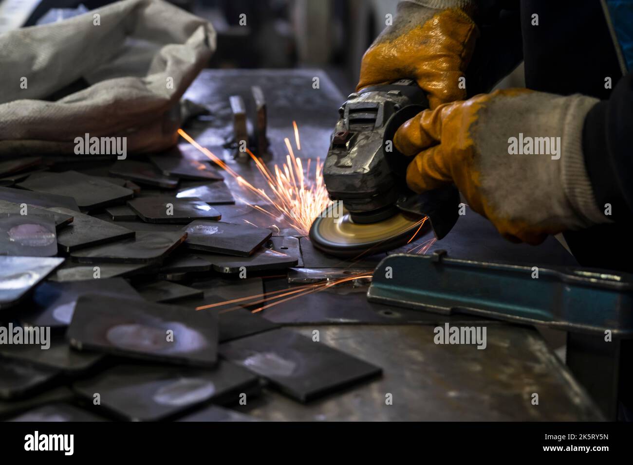 Grinding metal plates with electric wheel in factory. Sparks from the ...