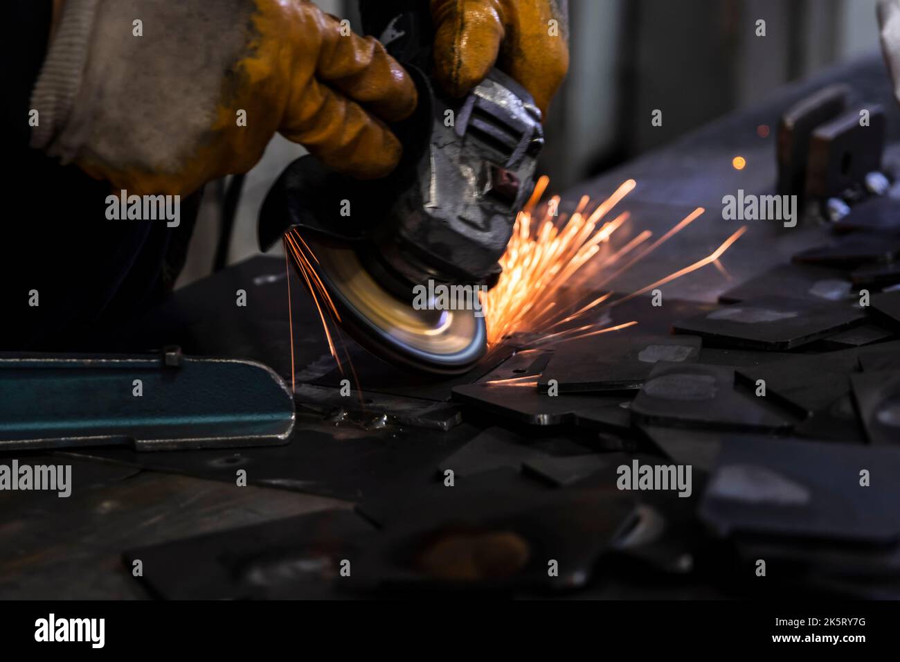Grinding metal plates with electric wheel in factory. Sparks from the ...