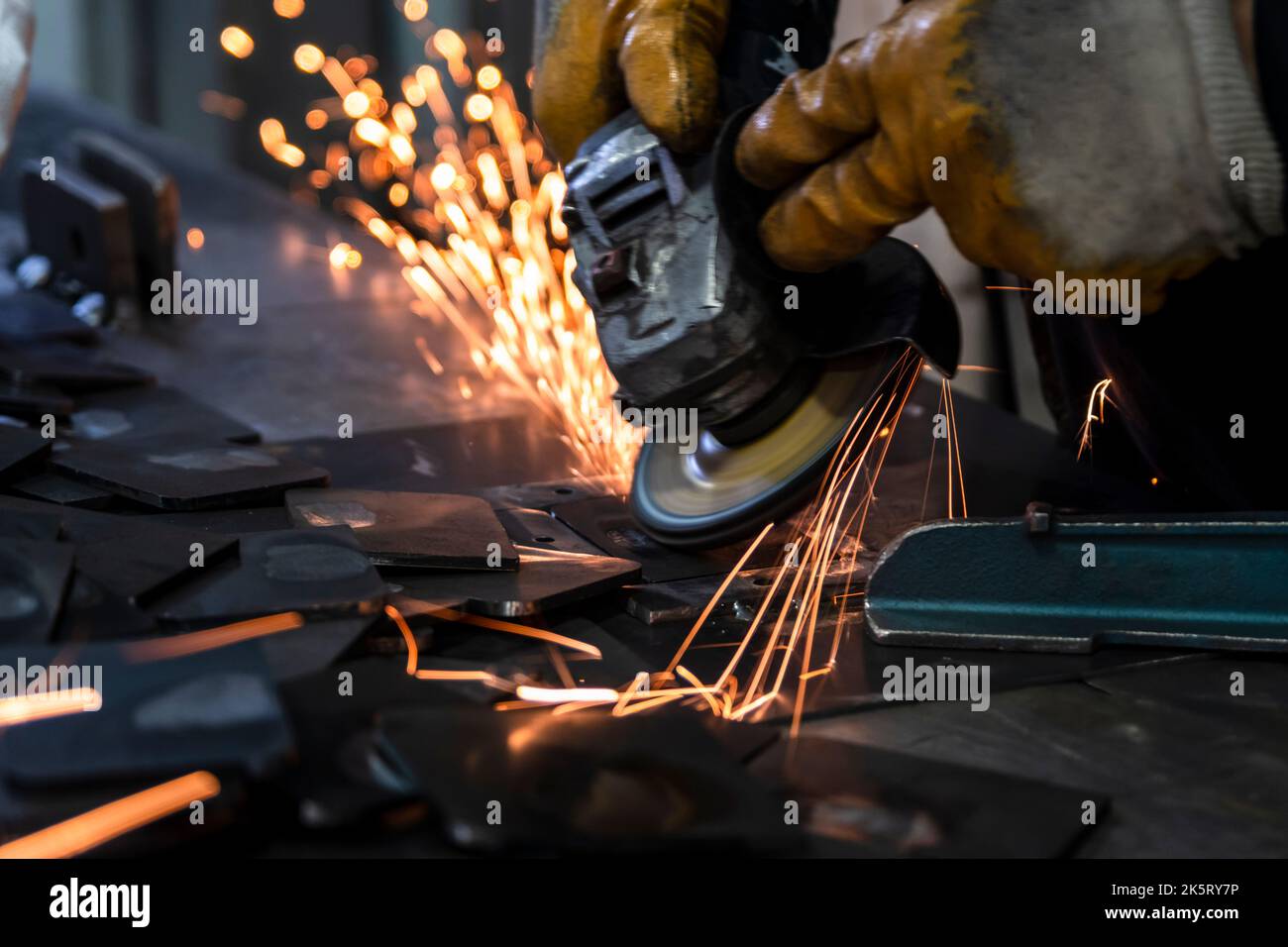 Grinding metal plates with electric wheel in factory. Sparks from the ...